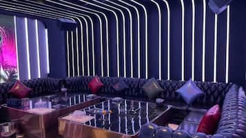 Espaço lounge moderno com sofá curvo e mesa de centro de vidro, apresentando um design de teto único com linhas verticais.