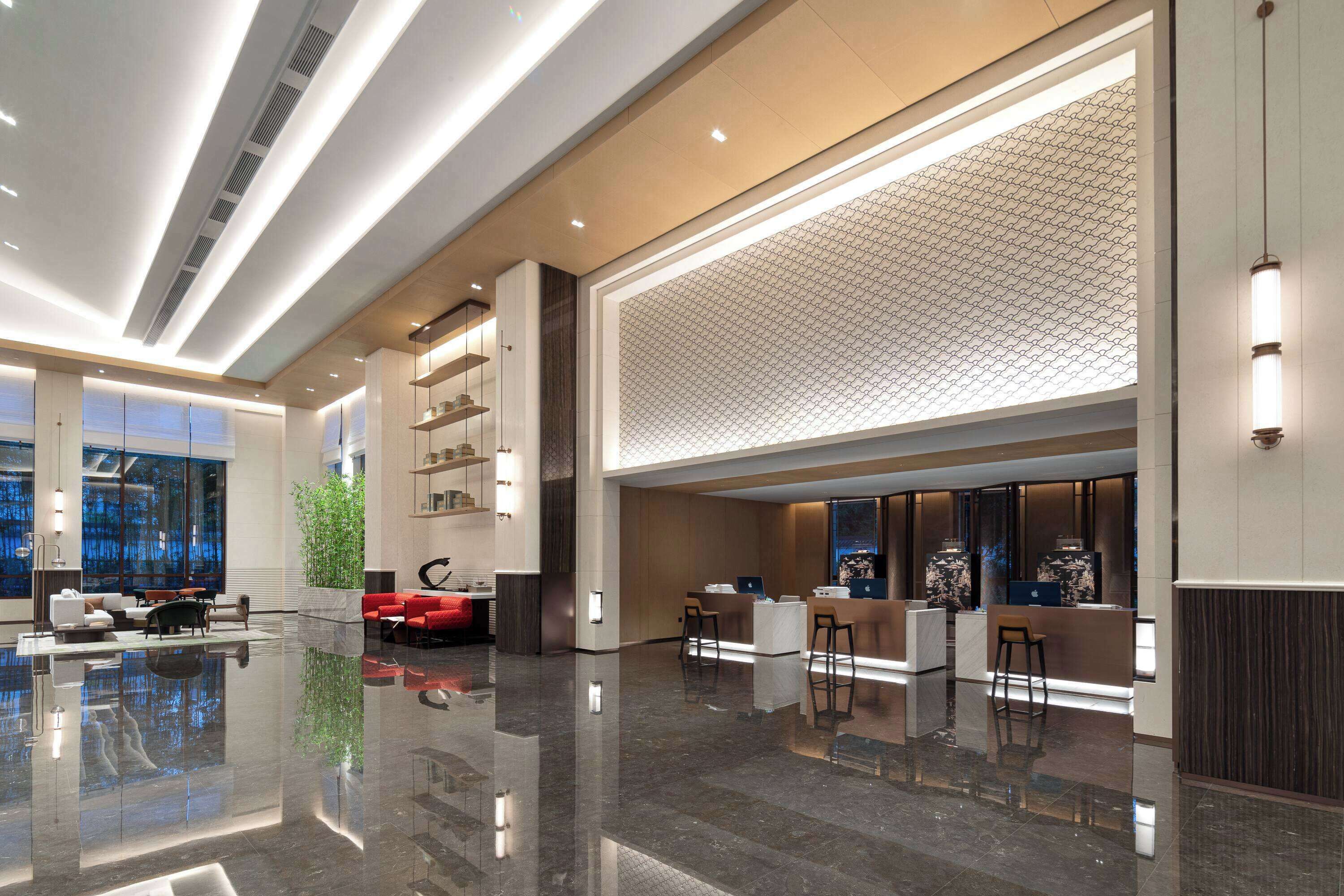 Um hall moderno com piso lustroso, áreas de estar e balcão de recepção.