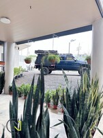 Um caminhão azul estacionado sob uma cobertura com plantas em vasos e teto branco.