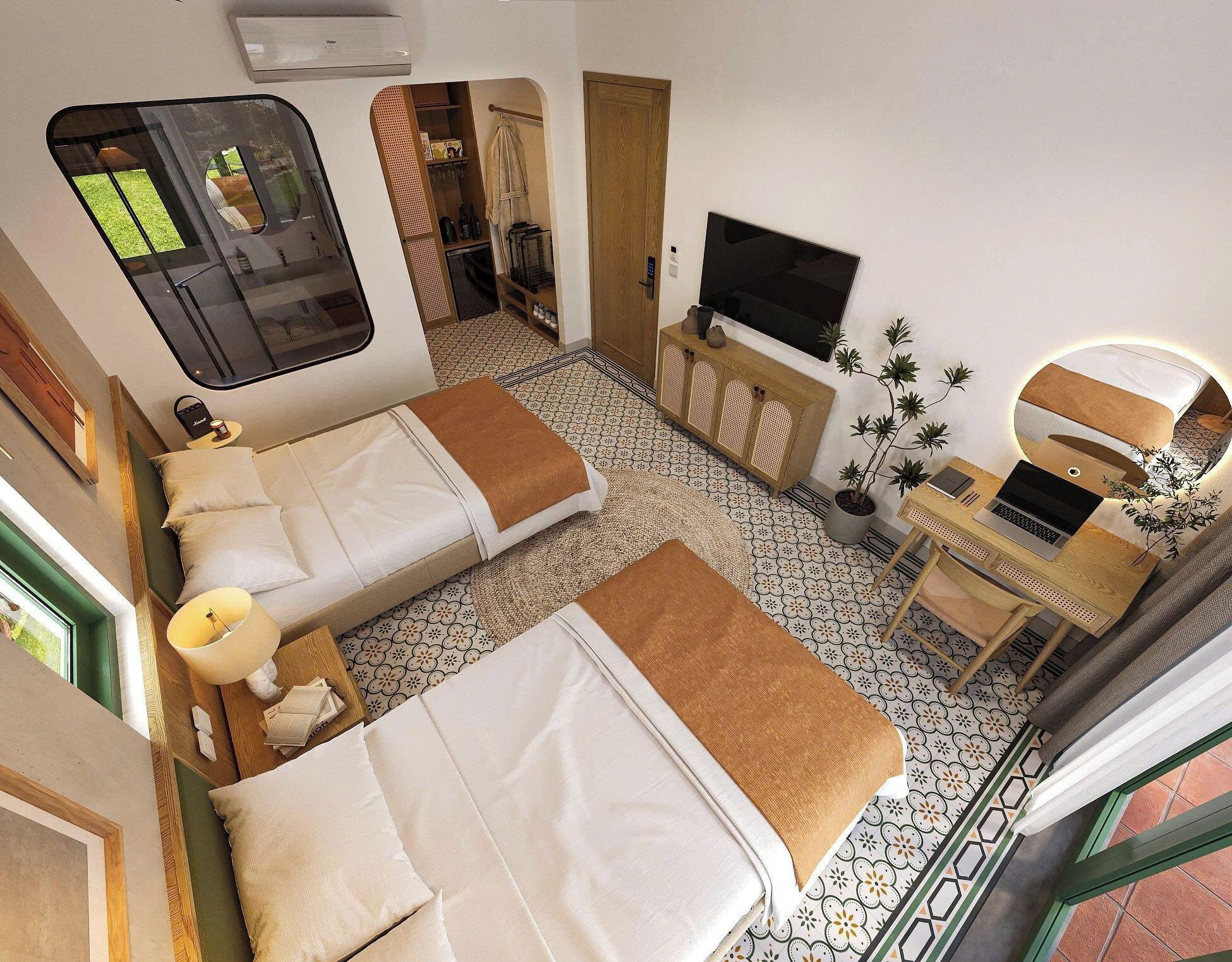Quarto de hotel com duas camas, uma televisão, uma secretária com um computador portátil, uma planta em vaso e uma janela com vista para o exterior.