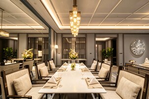 Uma sala de conferências com uma mesa comprida, cadeiras e um candelabro.