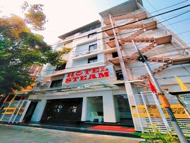 Um hotel com vários andares e uma placa grande com a inscrição 'HOTEL STEAM'.