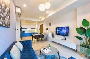Uma sala de estar moderna com um sofá azul, uma mesa de centro redonda e uma TV de tela plana fixada na parede.