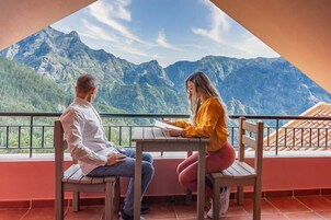 Duas pessoas sentadas à mesa com vista para a montanha.