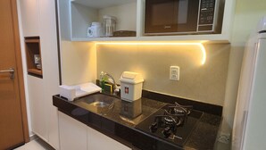 Cozinha moderna com armários brancos, bancada preta, micro-ondas embutido e fogão a gás.