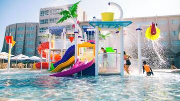 Parque aquático com toboáguas e atrações aquáticas, cercado por um edifício com vários andares e janelas.