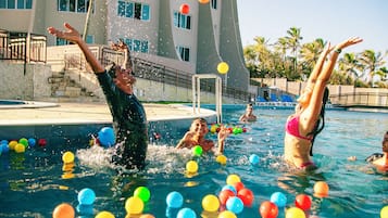 Piscina com balões coloridos e pessoas aproveitando a água.
