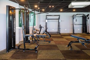 Uma academia com diversos equipamentos de exercícios, incluindo máquinas de peso e barra para puxada.