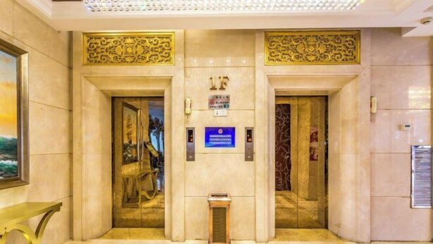 Um elevador com uma placa azul, um painel decorativo dourado e um pequeno pedestal no centro.