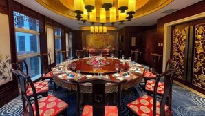 Uma mesa de jantar redonda com cadeiras, um candelabro e um quadro grande na parede.