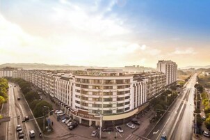 Um edifício de vários andares com fachada curva, cercado por ruas e outros edifícios.