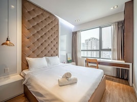 Quarto de hotel moderno com uma cama grande, vista da cidade pela janela e piso de madeira.