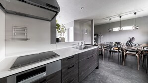 Uma cozinha moderna com forno embutido, pia e área de refeições com mesa e cadeiras.