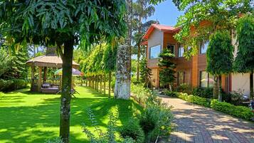 Jardim bem cuidado com um gazebo, um caminho pavimentado e um edifício moderno com grandes janelas.