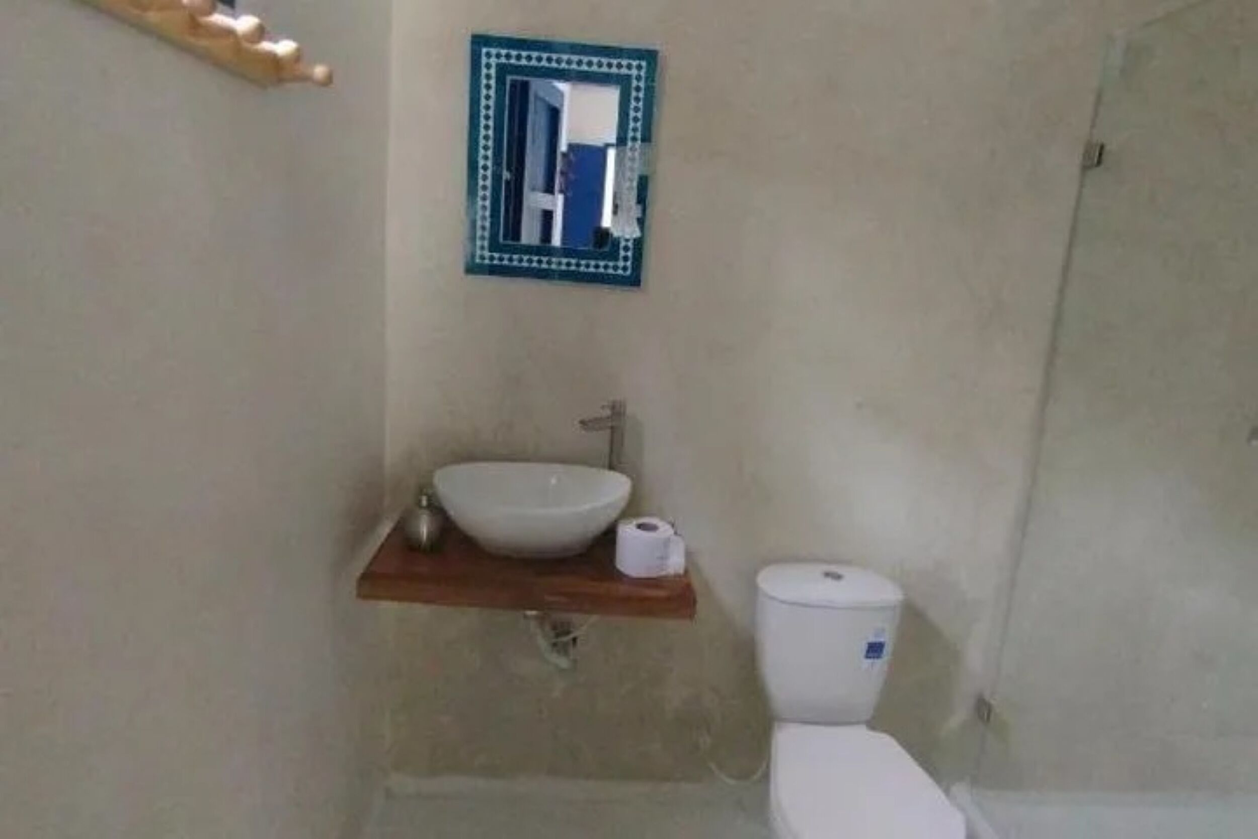 Um banheiro pequeno com vaso sanitário branco, pia branca e espelho com moldura azul.