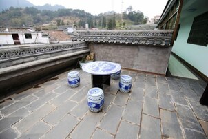 Um pátio em estilo tradicional chinês, com uma mesa redonda e quatro banquinhos de cerâmica azul e branca.