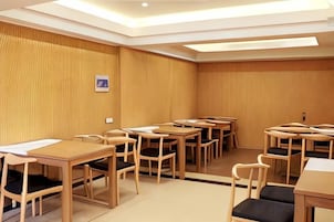 Uma sala de conferências com várias mesas e cadeiras, painéis de parede em madeira e um lustre.