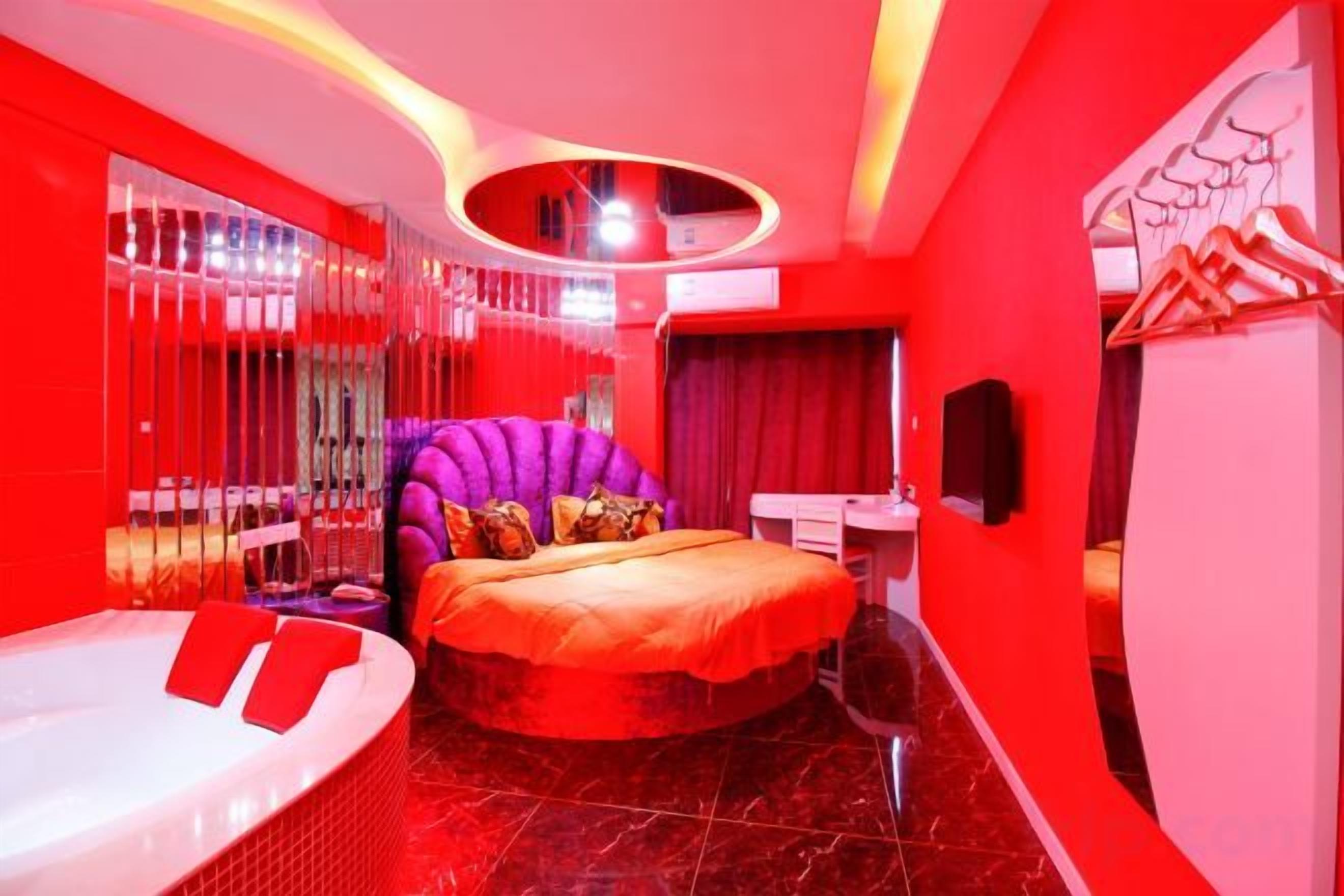 Quarto com cama grande, hidromassagem circular e decoração em tons de vermelho.