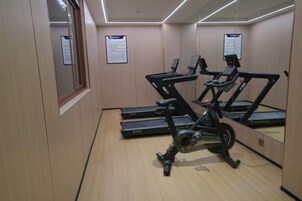 Academia com esteiras e bicicletas ergométricas, paredes de madeira e um espelho grande.