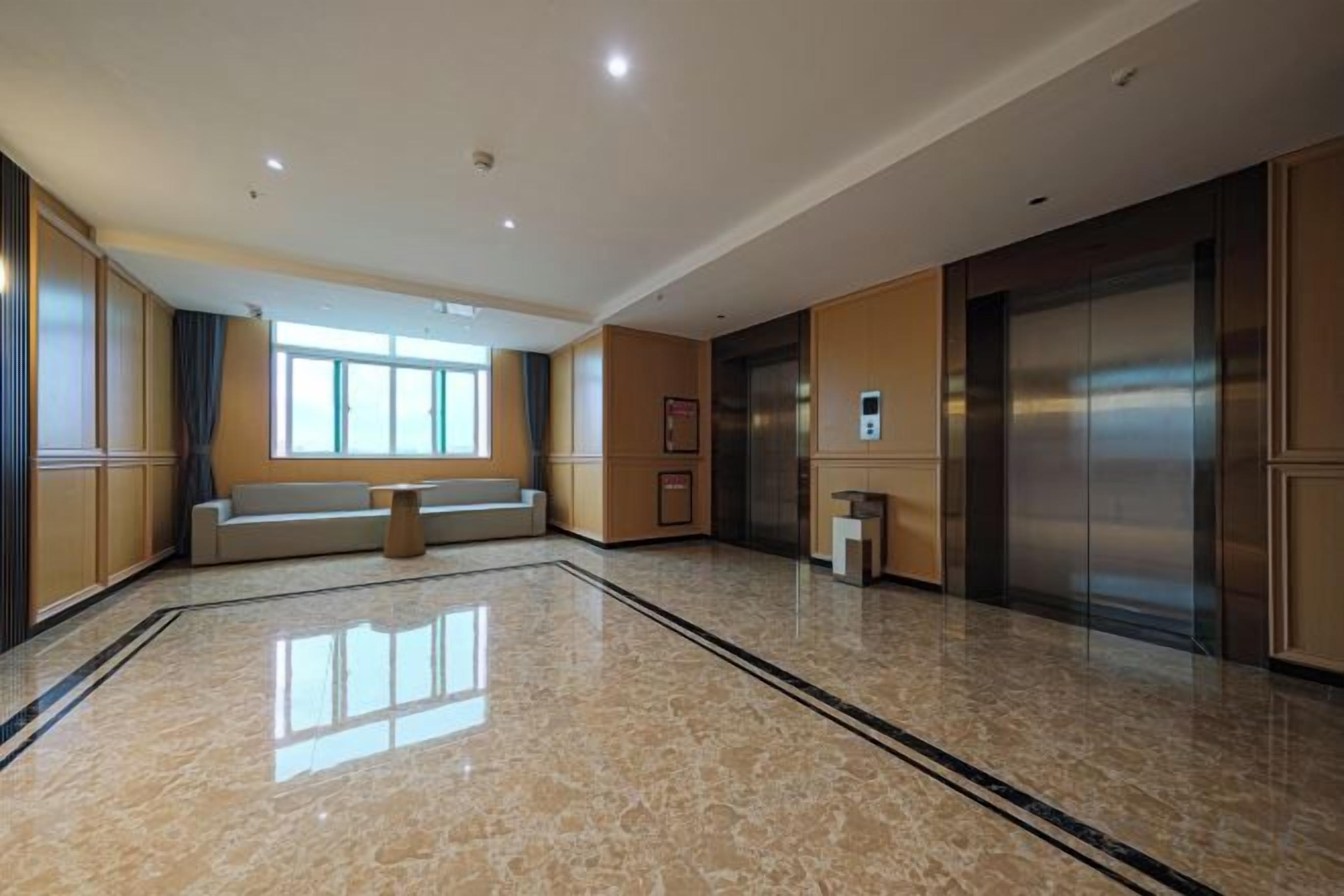 Um hall amplo com piso de mármore, área de estar e elevador.