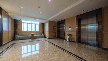 Um hall amplo com piso de mármore, área de estar e elevador.