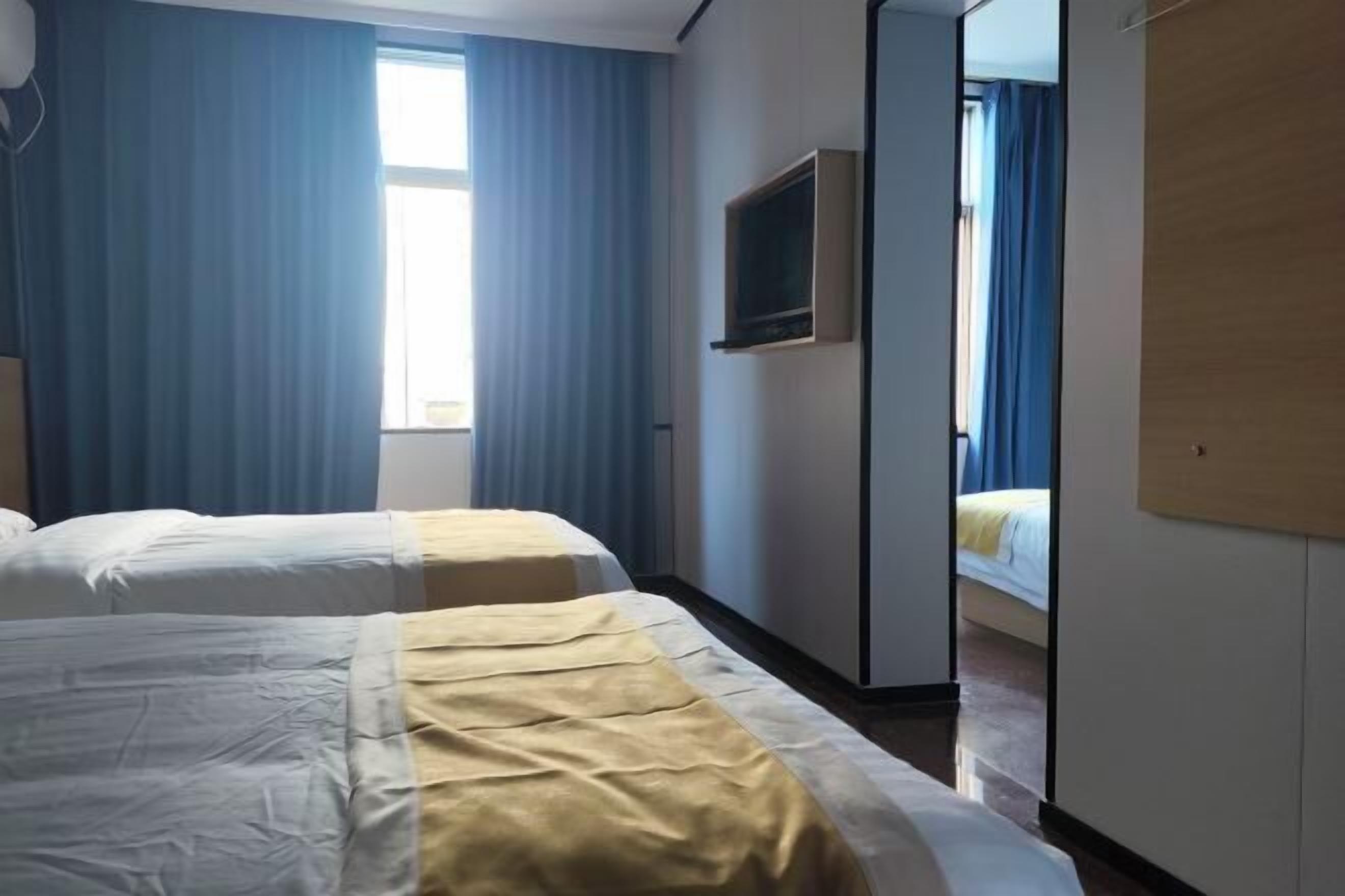 Quarto de hotel com duas camas, uma televisão e um espelho.