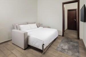 Quarto com cama, cadeira, tapete e porta para outro espaço.