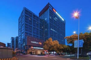 Um hotel moderno com um letreiro grande 'Wellton City', vários andares e fachada bem iluminada.