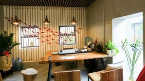 Uma área de refeições com mesa de madeira, cadeiras, decorações de peixes vermelhos pendurados e plantas em vasos.