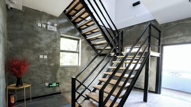 Um interior moderno com escada em espiral, paredes de concreto e uma pequena mesa com um vaso.