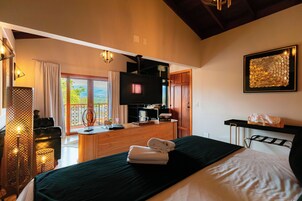 Quarto de hotel com cama, escrivaninha, televisão e vista para o exterior.