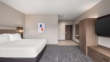 Quarto de hotel moderno com uma cama grande, televisão de tela plana, guarda-roupa e uma obra de arte emoldurada na parede.
