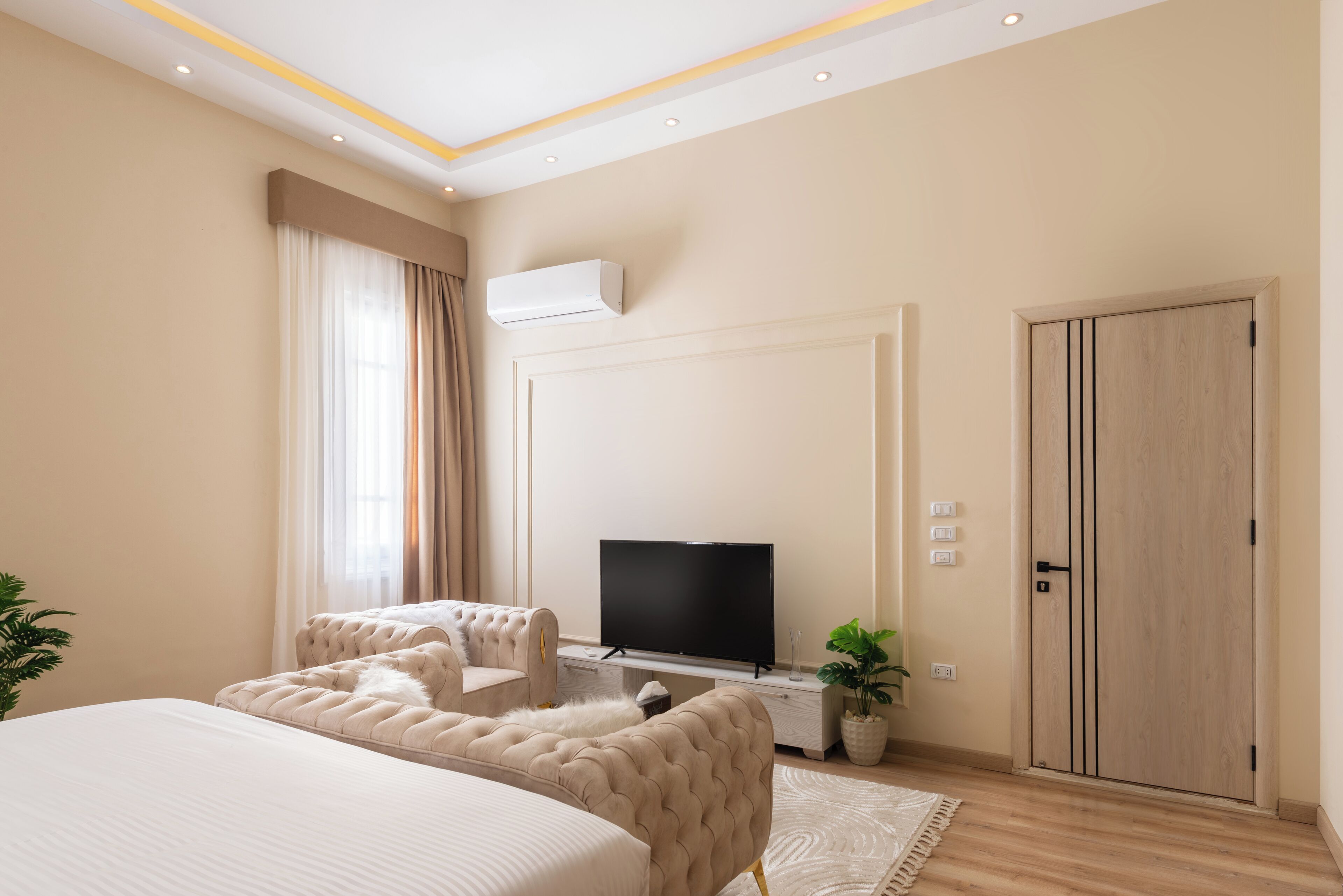 Quarto de hotel moderno com uma cama grande, um sofá, uma televisão e um guarda-roupa.