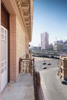 Uma varanda com vista para uma rua movimentada e edifícios altos ao longe.
