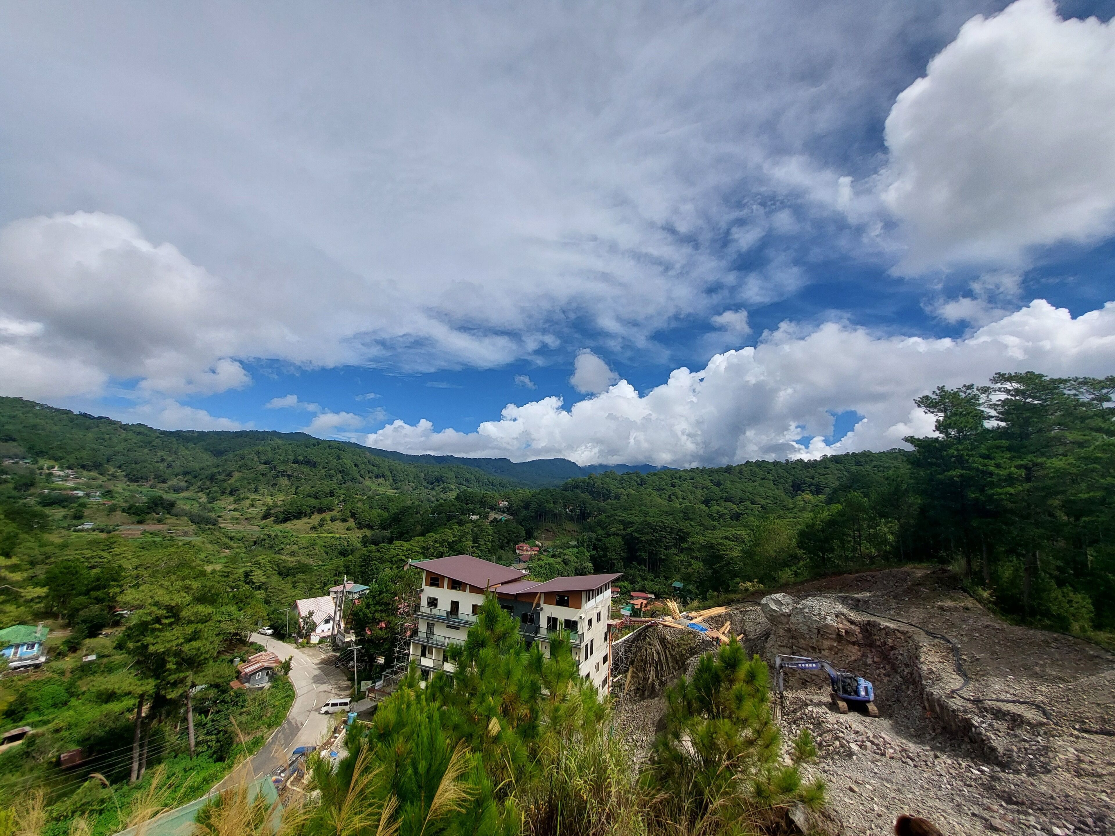 Paisagem montanhosa com um edifício rodeado por vegetação exuberante.