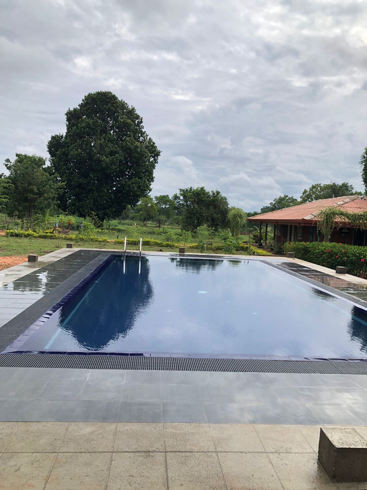 Uma piscina retangular com um deck ladrilhado em primeiro plano.