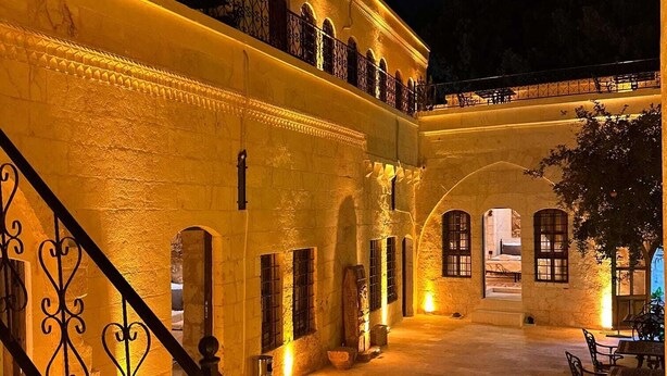 Pátio com escadaria que leva a uma varanda, rodeado por paredes e arcos de pedra.