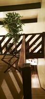 Uma escadaria com corrimão de madeira, uma planta e uma mesa com objetos sobre ela.