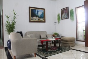Uma sala de estar com sofá, poltrona, mesa de centro e um quadro na parede.