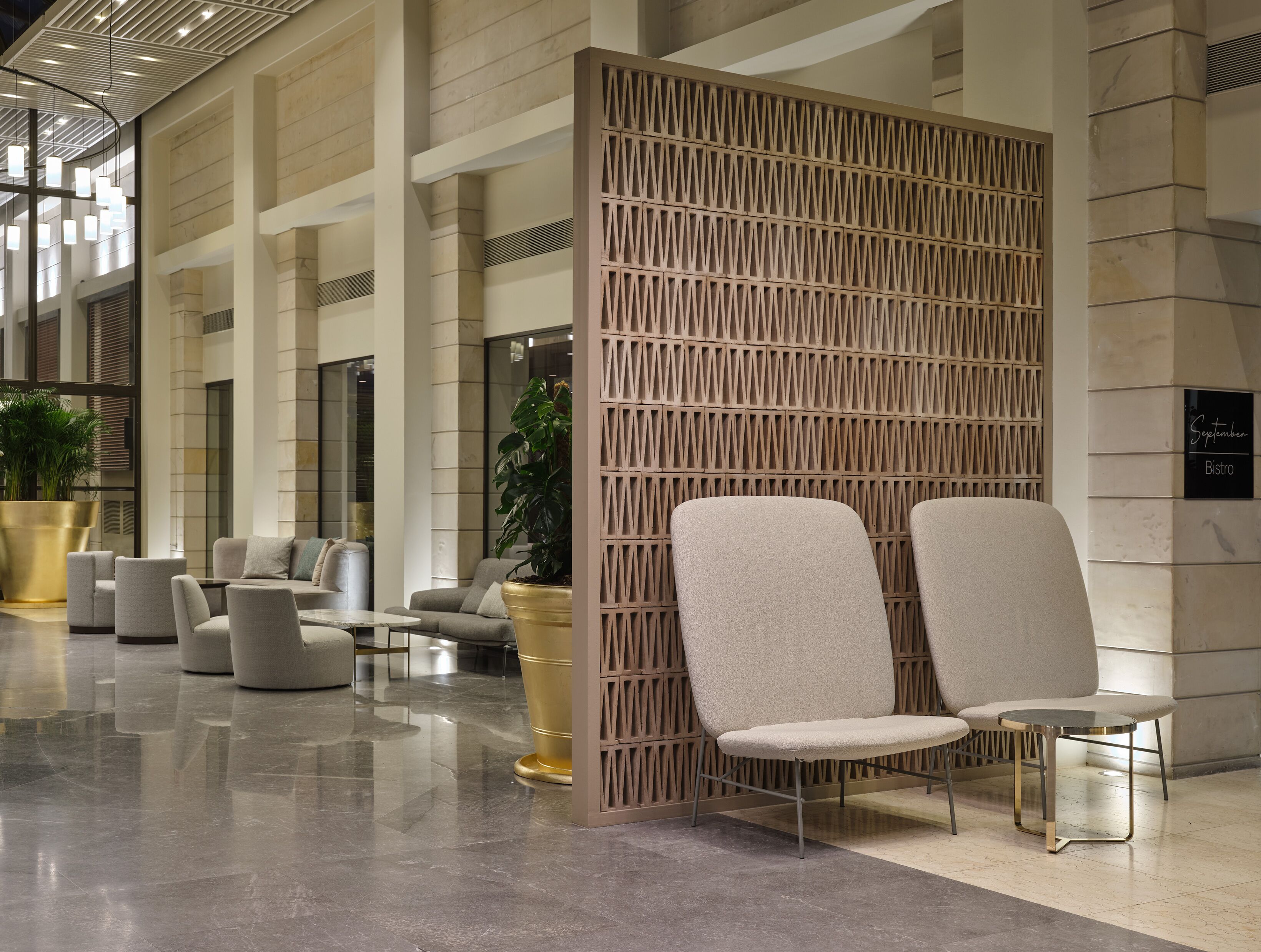 Um lobby moderno com áreas de estar, uma parede decorativa e uma placa indicando um bistrô.
