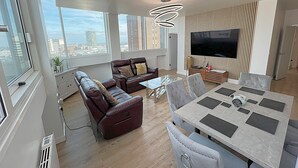 Uma sala de estar moderna com um sofá, uma mesa de jantar e uma televisão.