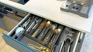 Uma gaveta de cozinha com utensílios e uma cafeteira.