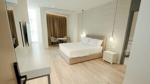 Quarto de hotel moderno com uma cama grande, mesas de cabeceira, escrivaninha e uma cadeira.