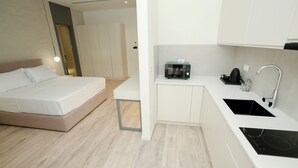 Quarto de hotel compacto com cama, cozinha compacta e banheiro pequeno.