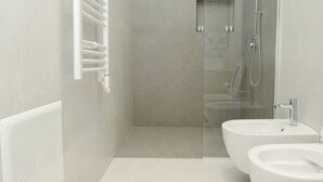 Um banheiro moderno com box de vidro, duas pias e um porta-toalhas.