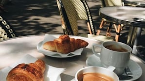 Uma mesa com um croissant, duas chávenas de café e um guardanapo.