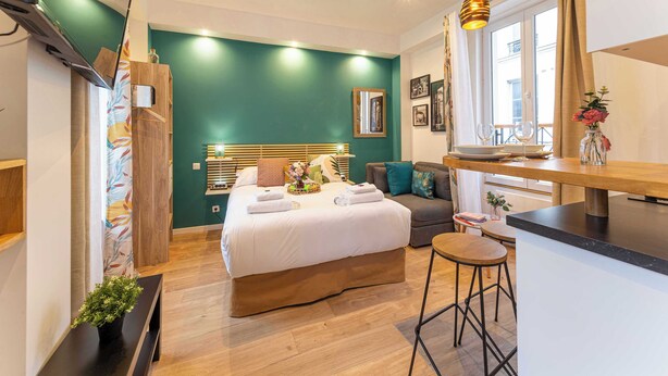 Quarto moderno com uma cama grande, um espaço de estar pequeno e uma cozinha compacta.