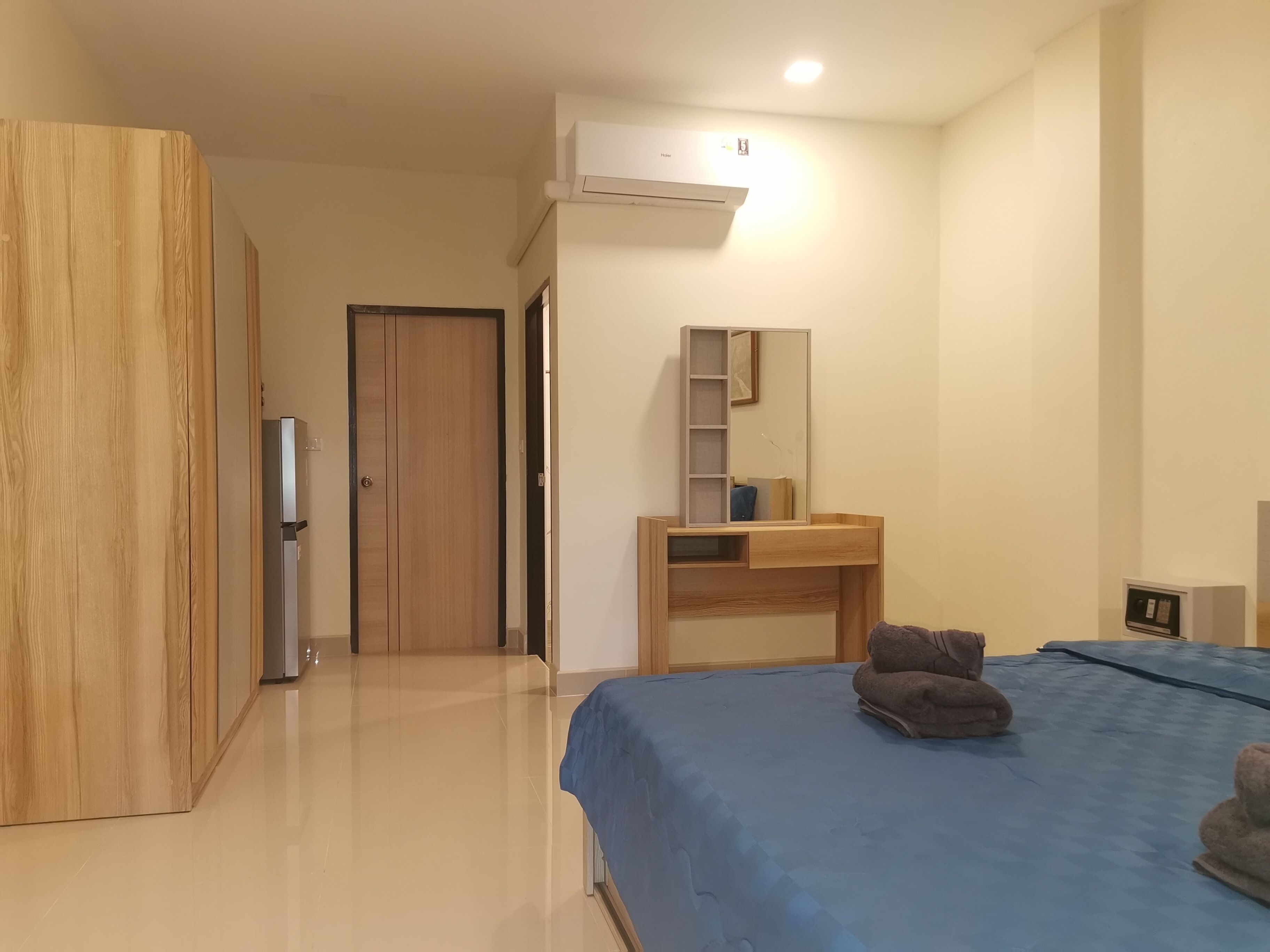 Quarto com cama, guarda-roupa de madeira, espelho e mesinha de cabeceira.
