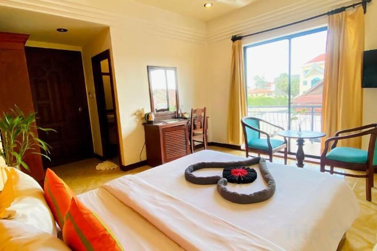 Quarto de hotel com cama, escrivaninha, cadeira e vista para o exterior.