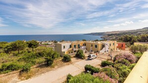 Uma área residencial costeira com edifícios, uma estrada e vista para o mar.